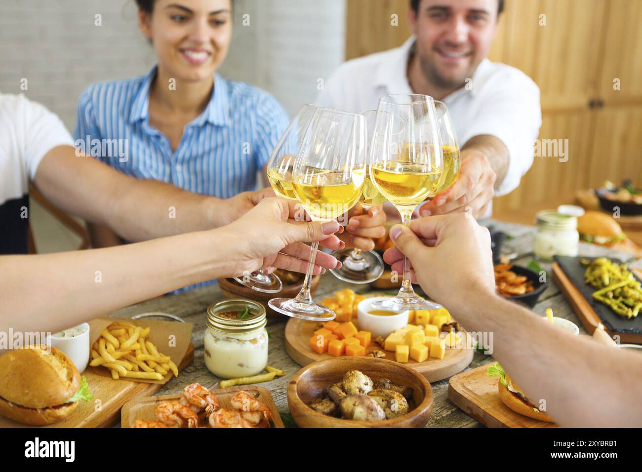 Hands with white wine toasting over served table with food. Friendship ...