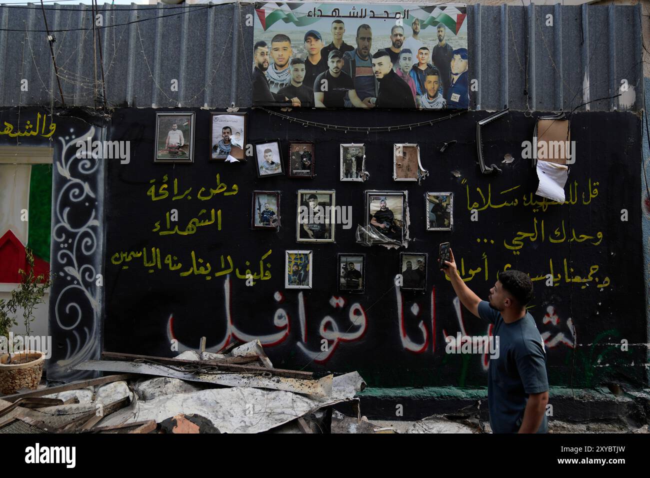 A man takes a picture of a wall displaying photos of Palestinians, who ...