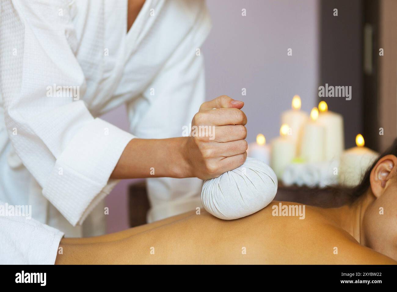 Beautiful young woman having back massage with pouch of rice. Close up ...