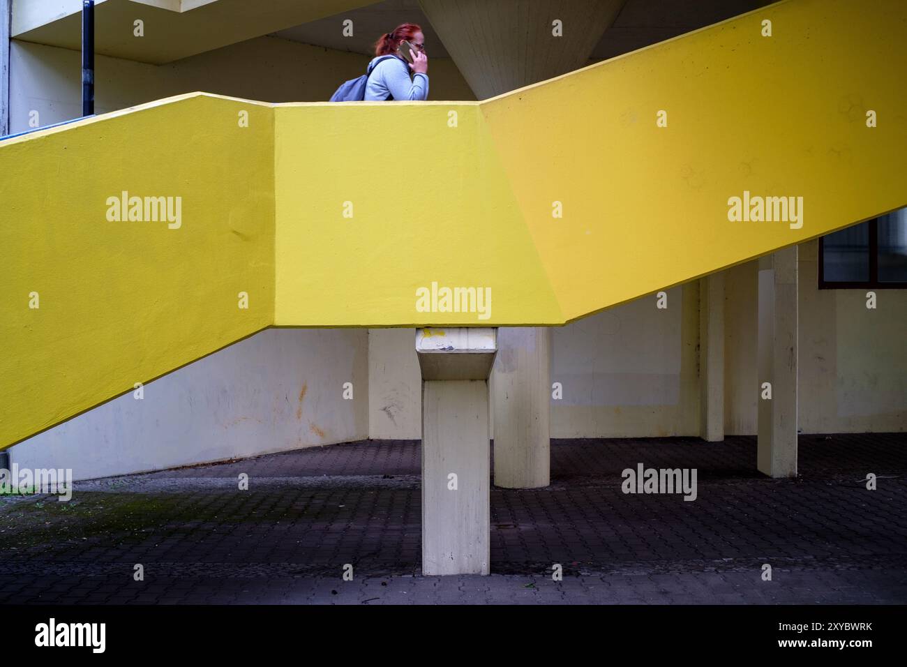 BERLIN, GERMANY - MAY 2021: Woman rushes up yellow stairs at housing ...
