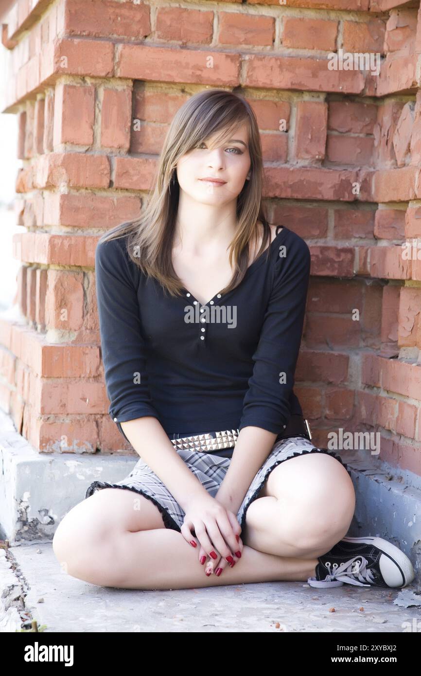 Young Girl Sitting Near A Brick House Stock Photo - Alamy