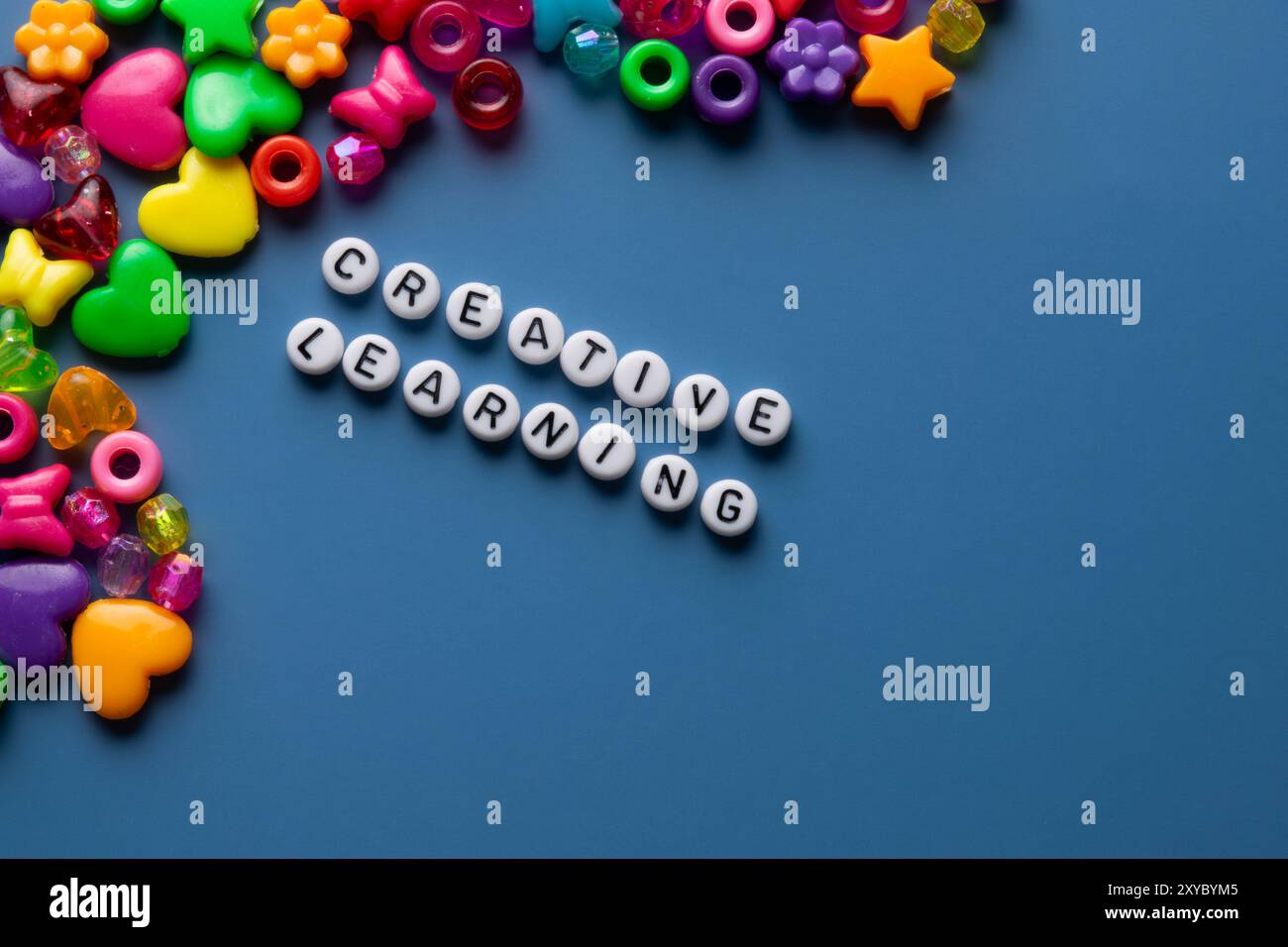 A collection of colorful beads is spread out across a blue background ...