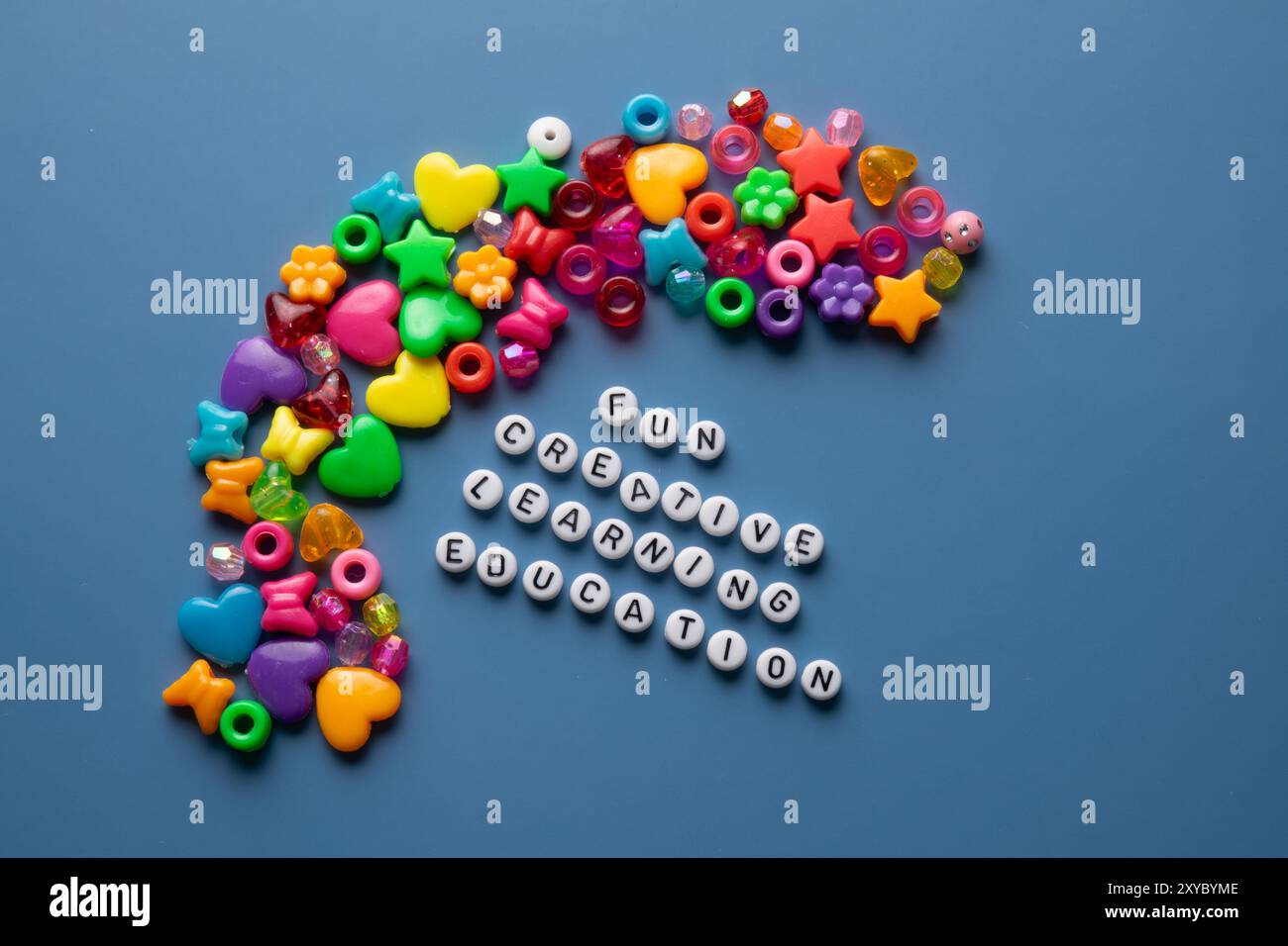 A collection of colorful beads is spread out across a blue background ...