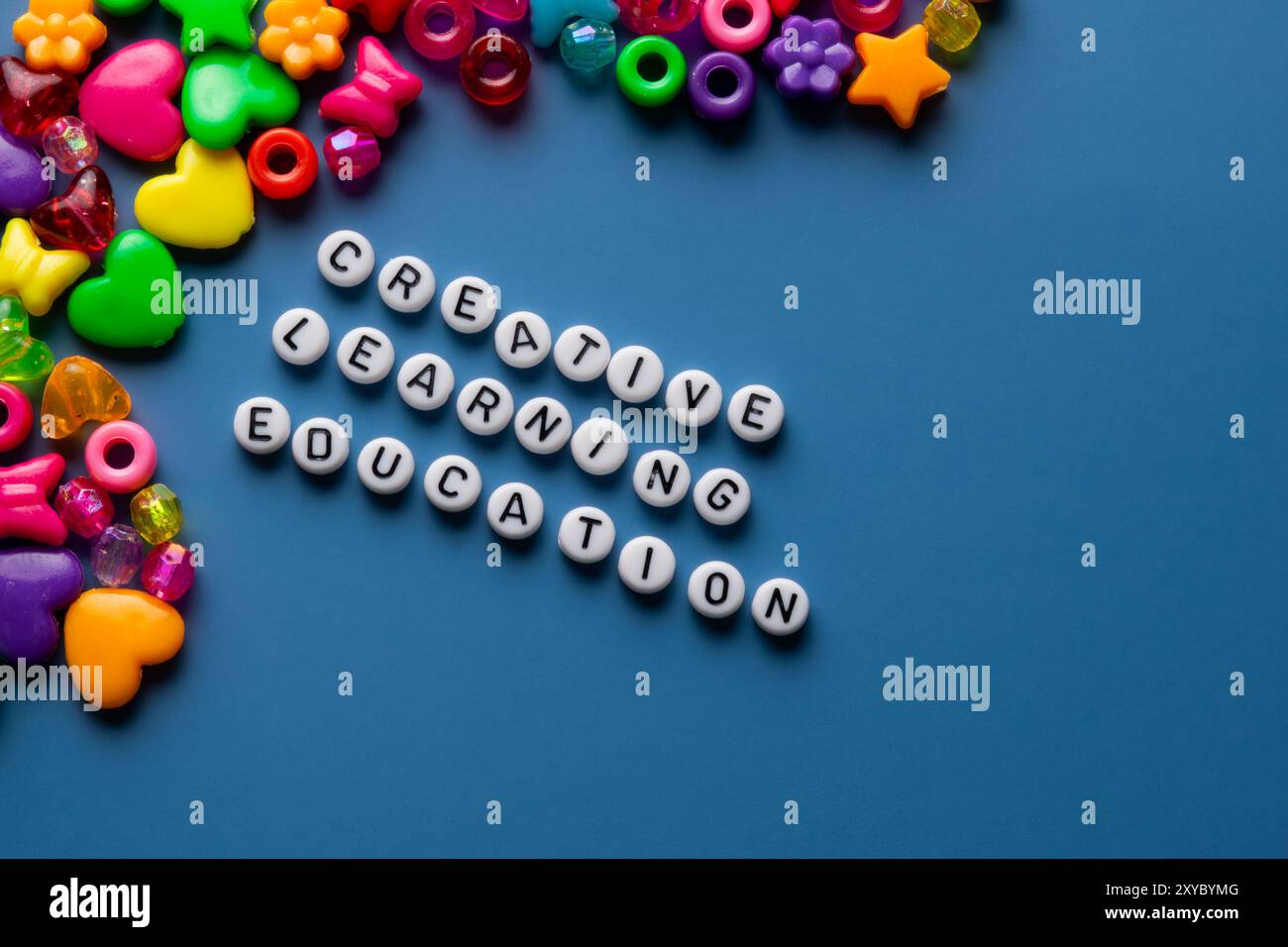 A collection of colorful beads is spread out across a blue background ...