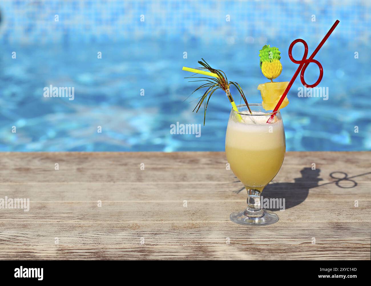 Glass of pinacolada cocktail standing on the swimming pool ledge in an ...