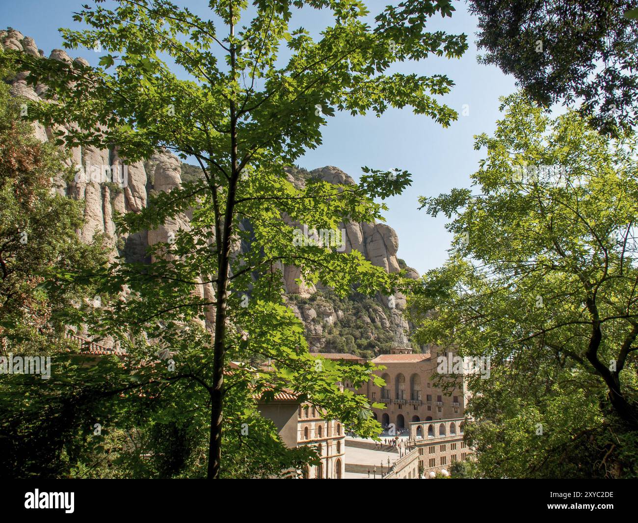 Building nestled between green trees and rocky mountains, in sunny ...