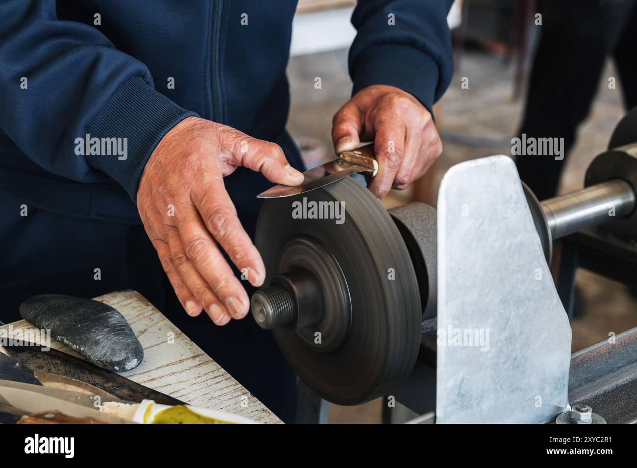grinder sharpens the knife by holding it in hands on the abrasive ...