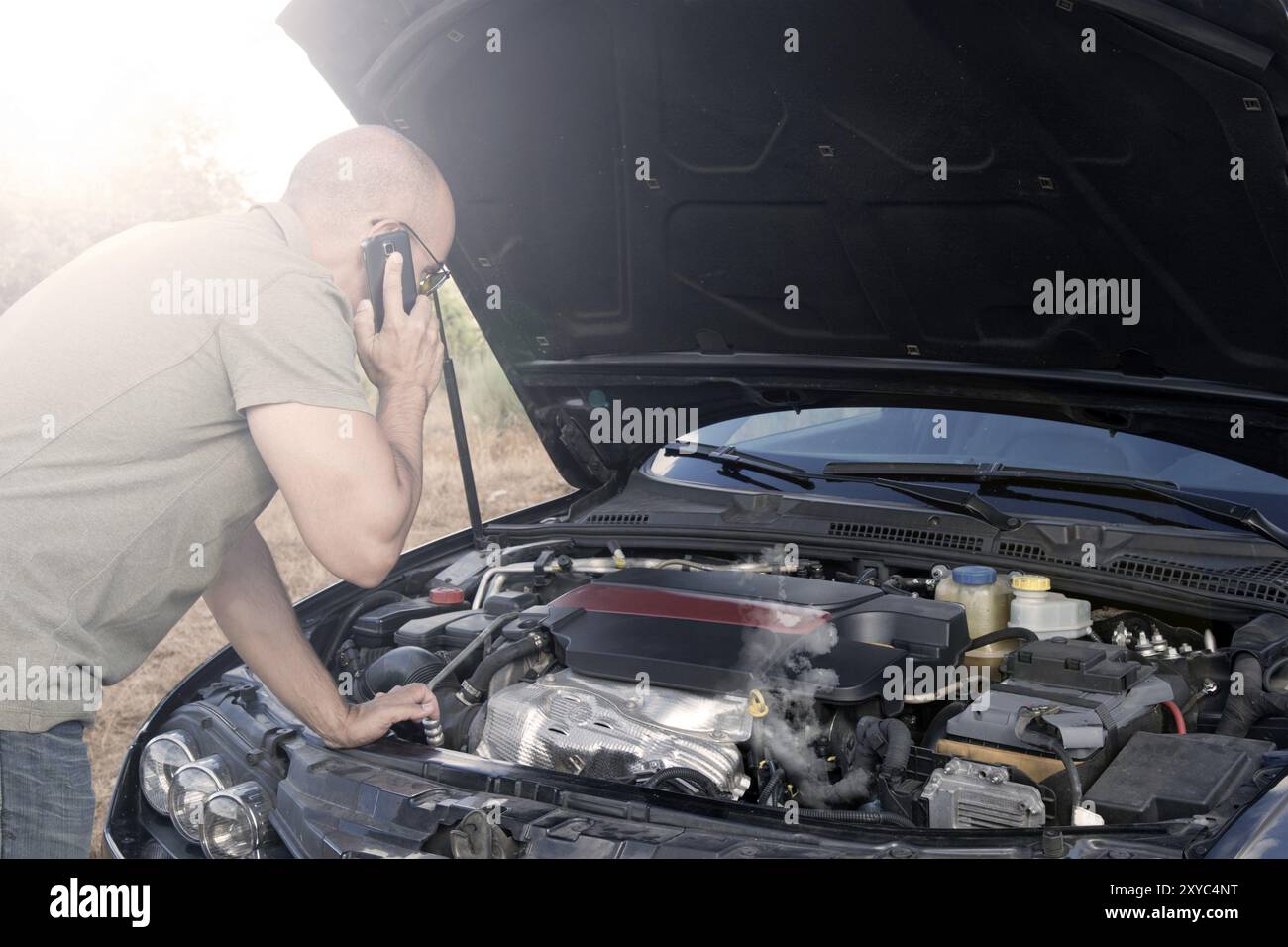 Close up of a broken down car, engine open and smoking, in a rural area ...