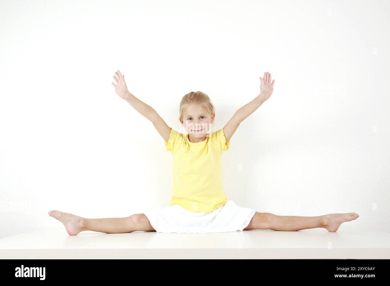 Cute little girl making splits on white background Stock Photo - Alamy