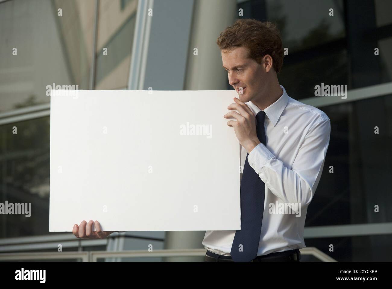 A cheerful businessman staring at a blank poster sign outside of a ...