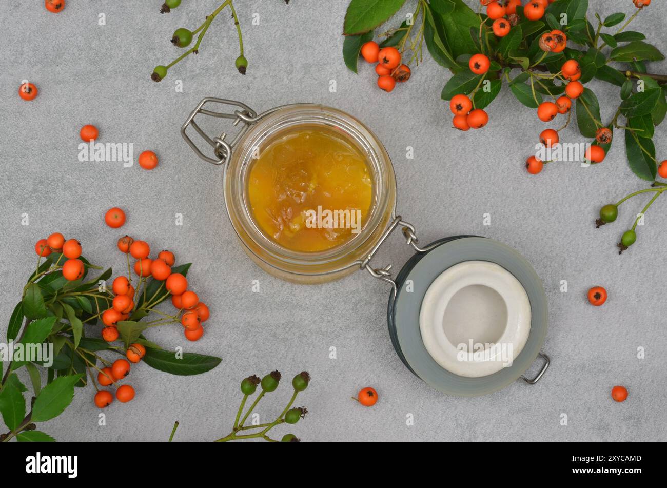 Orange/golden jam in a glass jar decorated with mountain ash and green ...
