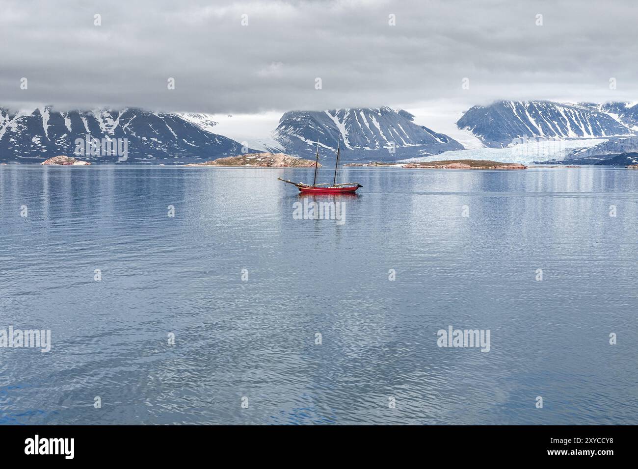 Glacier, mountains and sailing ship in a cloudy day in Svalbard islands ...