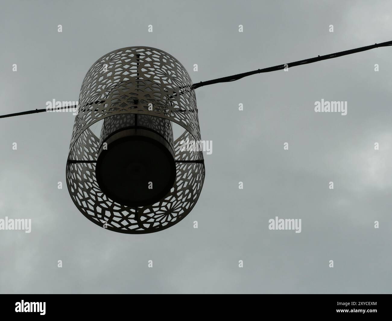 Metallic pendant light with laser-cut patterns on a cable, urban light ...