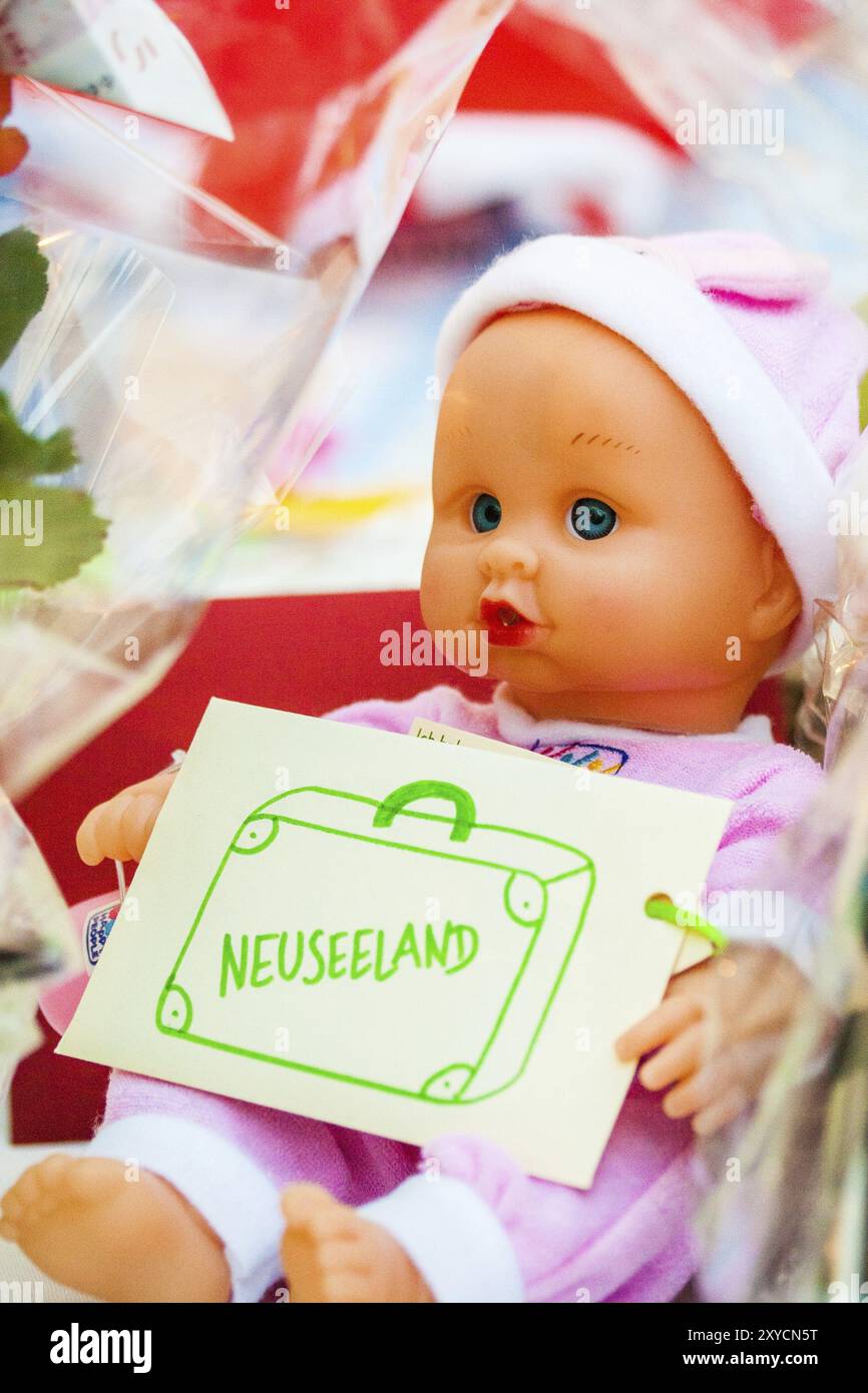 Baby doll holding sign with New Zealand written on it Stock Photo - Alamy