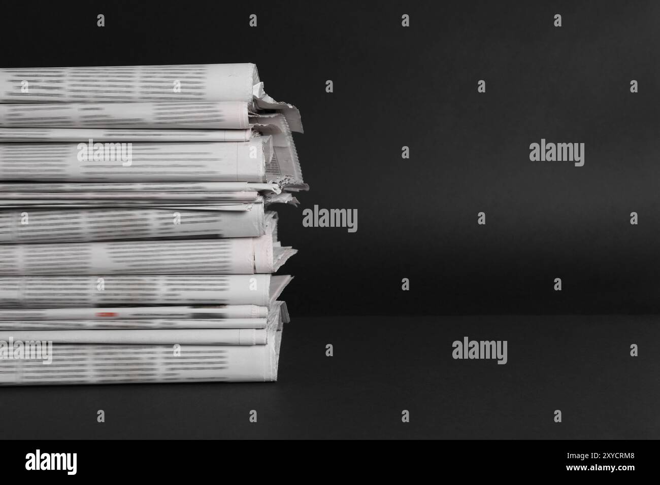 Stack of newspapers in different languages on black background. Space ...