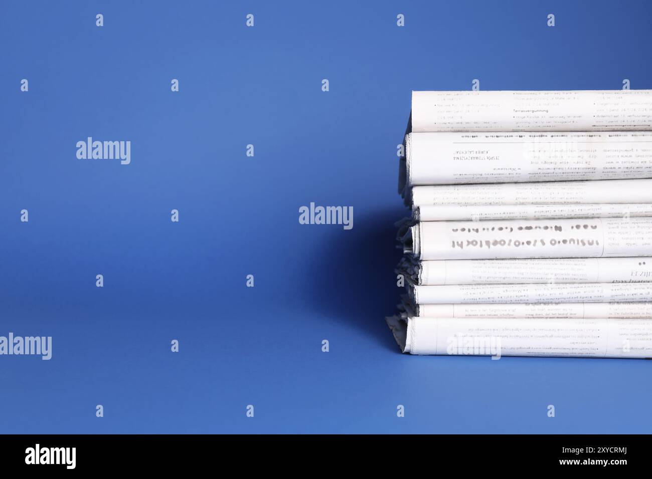 Stack of newspapers in different languages on blue background, space ...