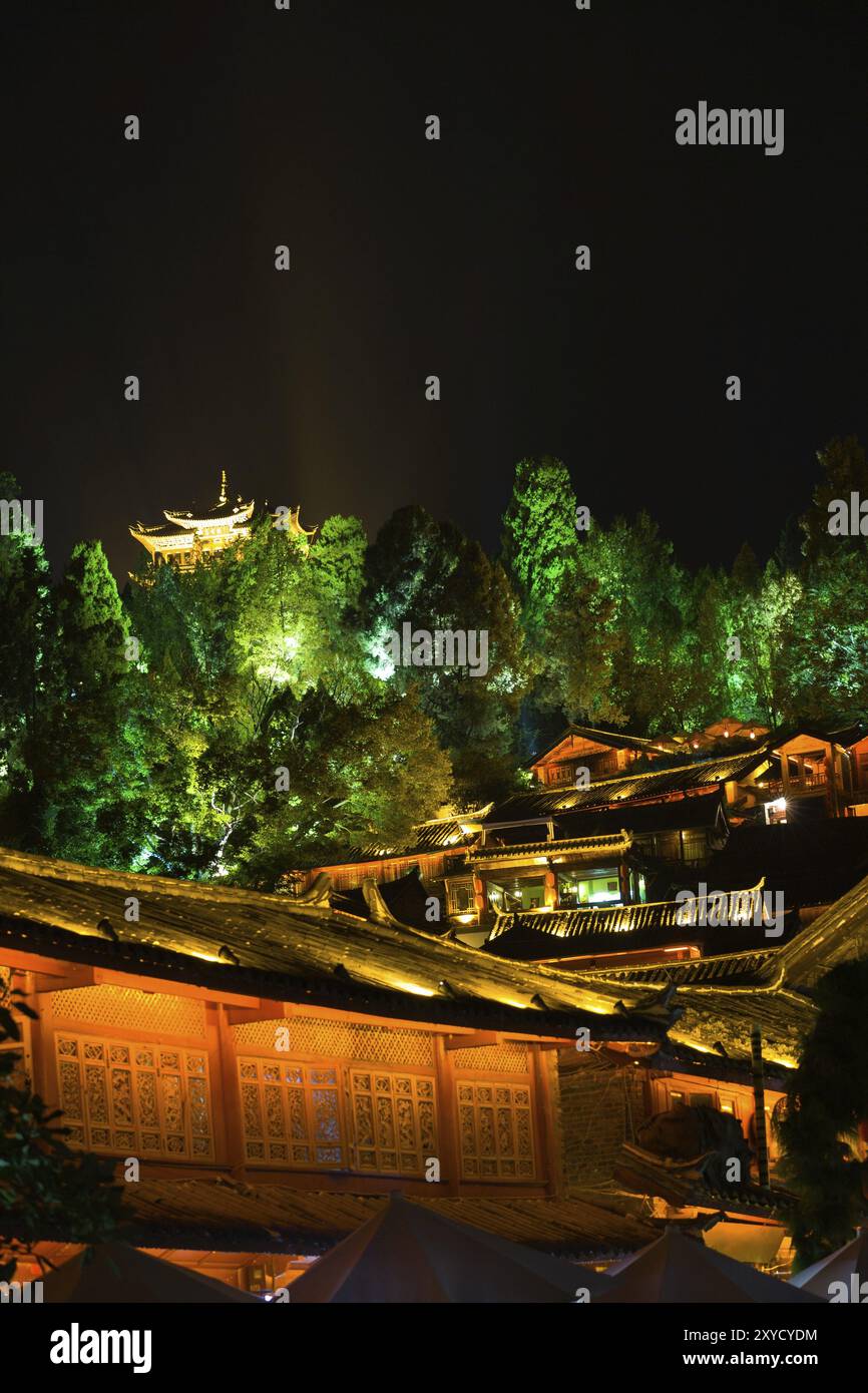 Old town buildings and hilltop pagoda illuminated at night in the ...