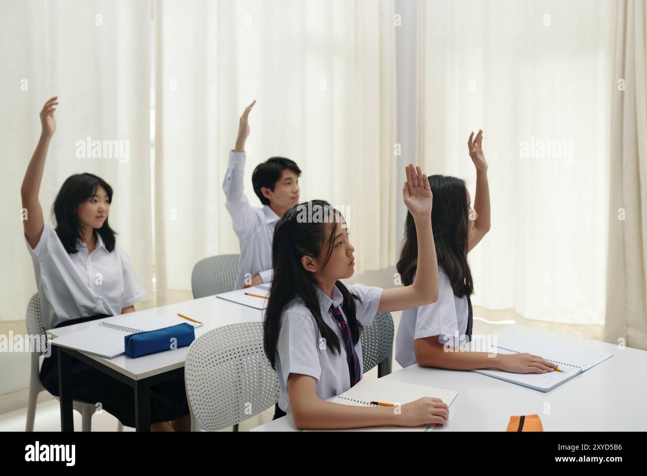 Students Raising Hands During Classroom Lesson Stock Photo - Alamy
