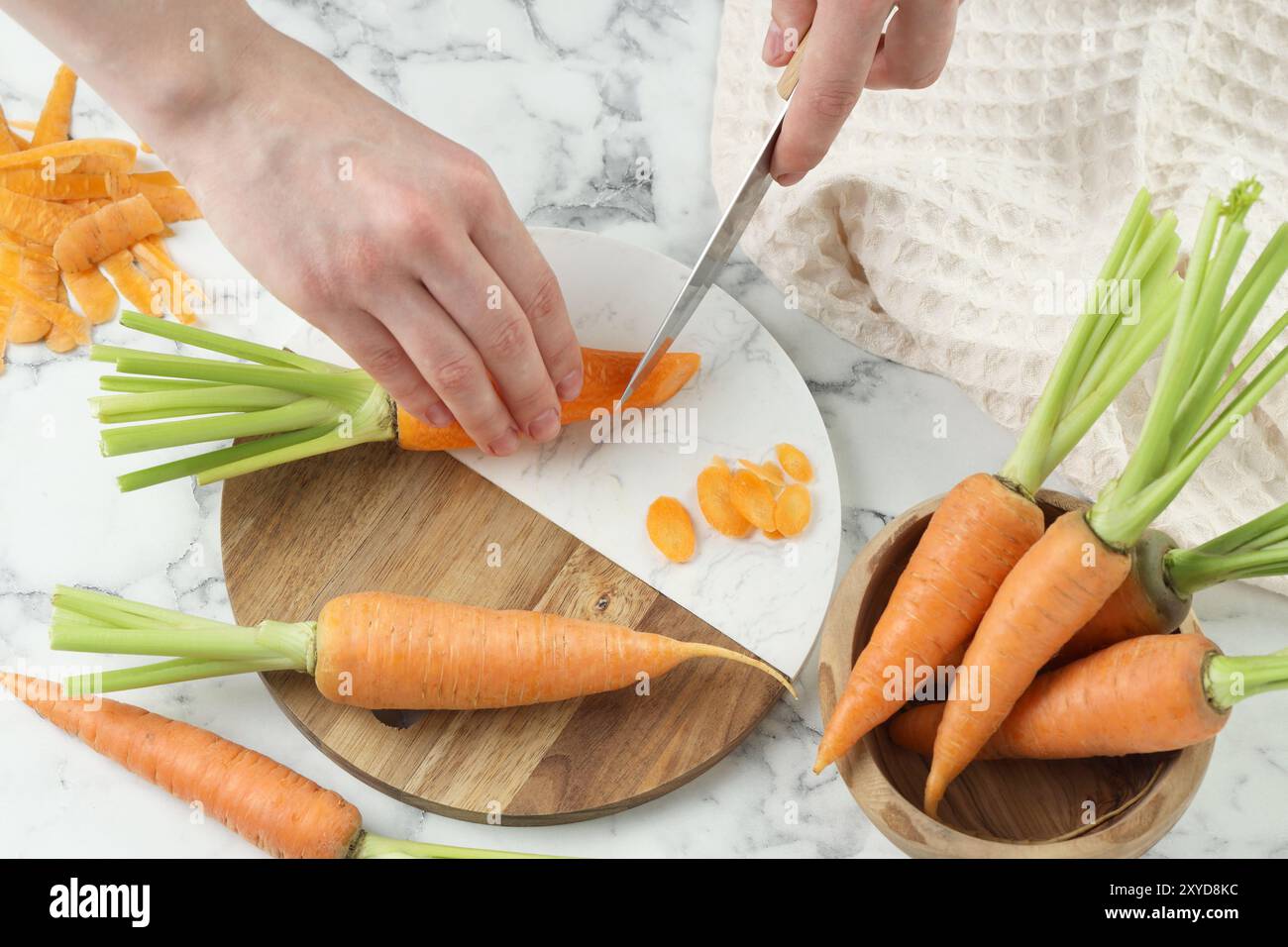 Woman cutting fresh carrot at white marble table, top view Stock Photo ...