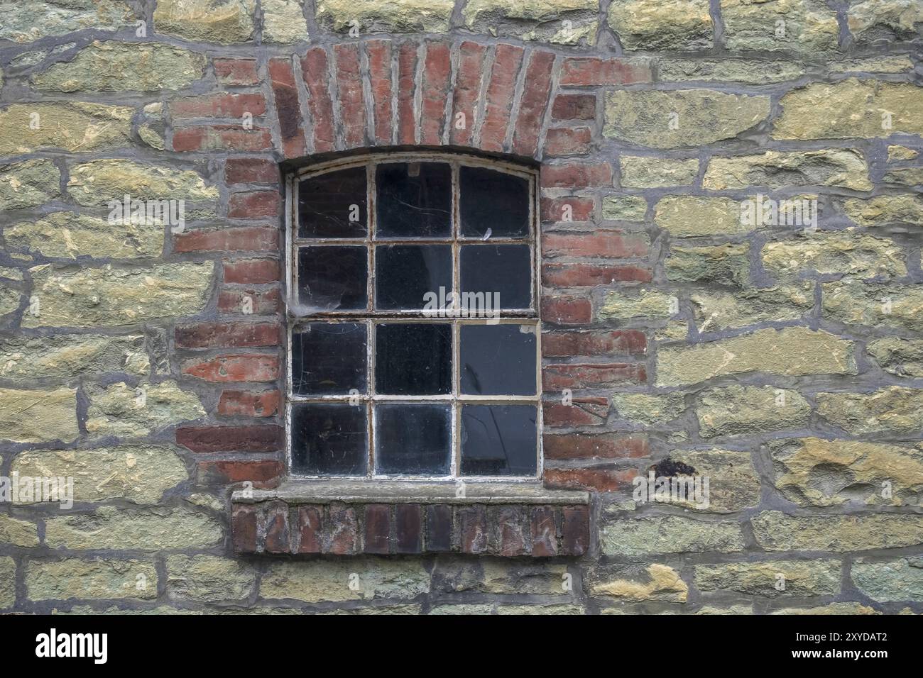 Single window embedded in a masonry stone wall with brick frame in an ...