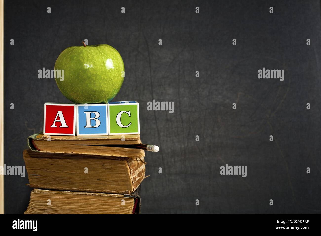 ABC and green apple on old textbook against blackboard in class. School ...