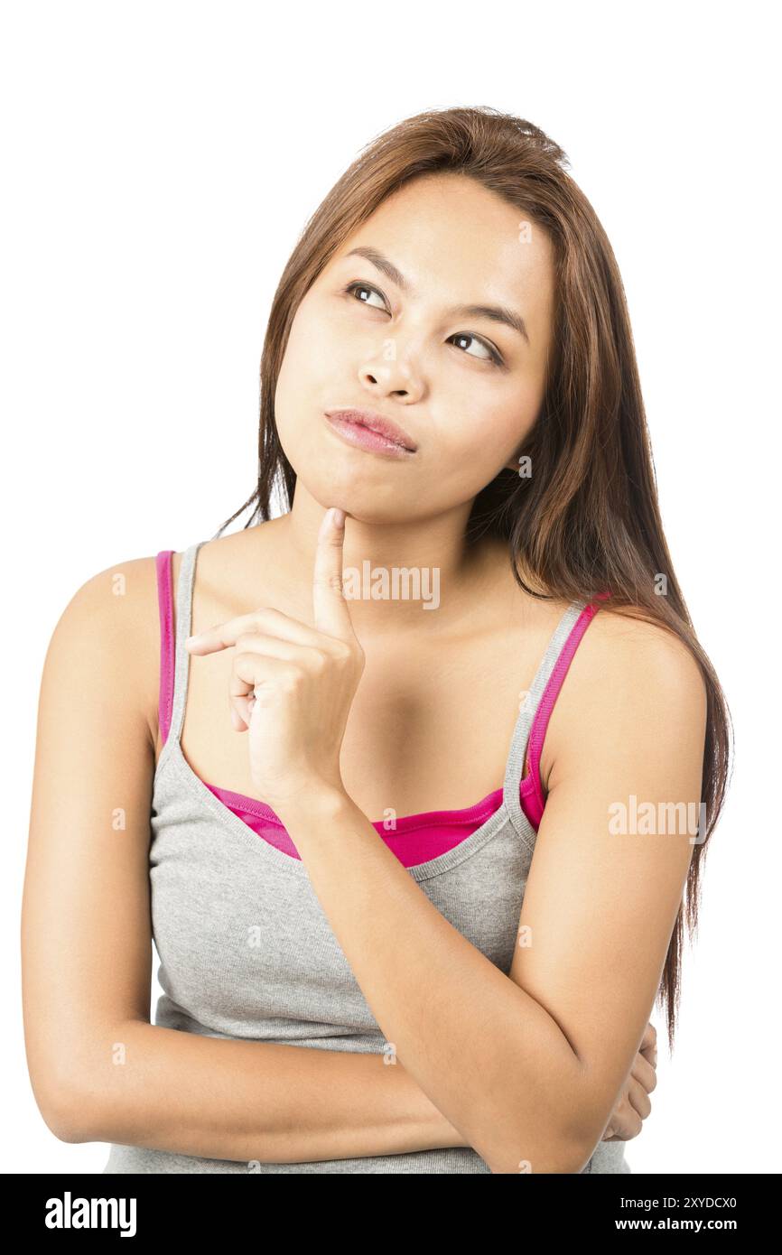Pensive Asian female in gray tank top, arms crossed, finger under chin looking up and away from ...