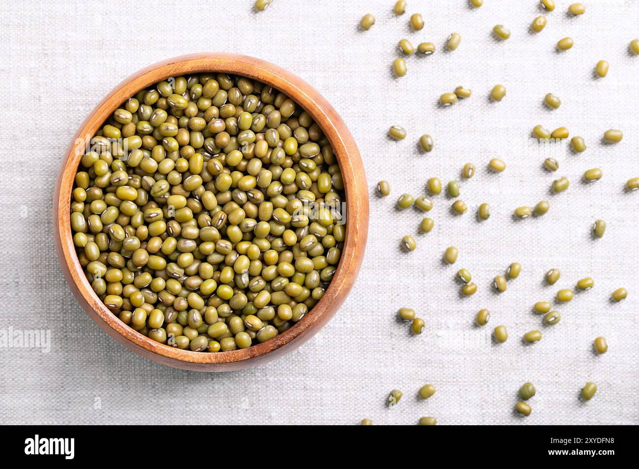 Mung beans, green gram in a wooden bowl on linen fabric. Dried seeds of ...