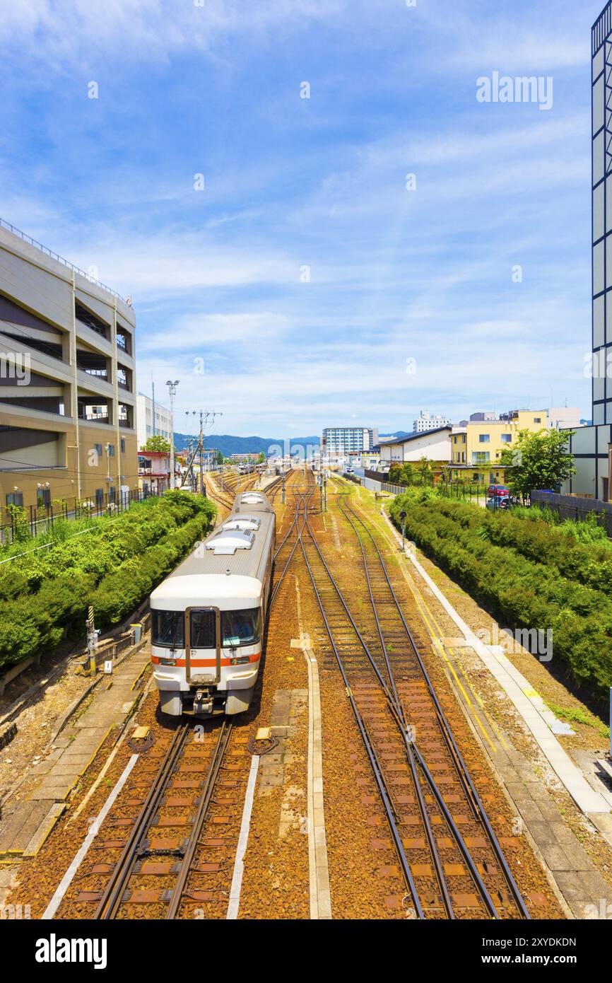 Oncoming train cars from Hida-Takayama train station along a pair of tracks on a beautiful ...