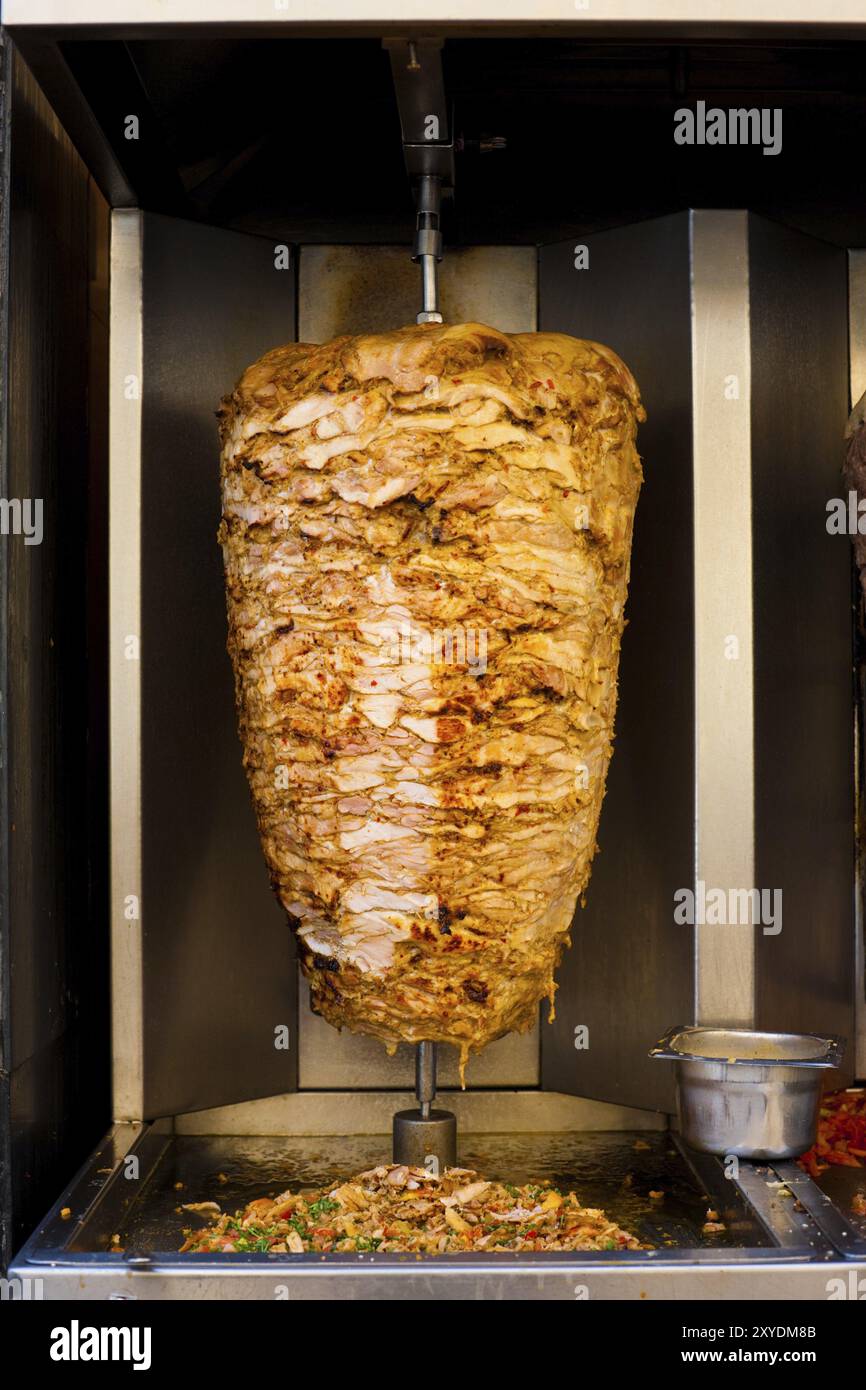A machine slowly grills a skewered mass of chicken, a typical meat ...