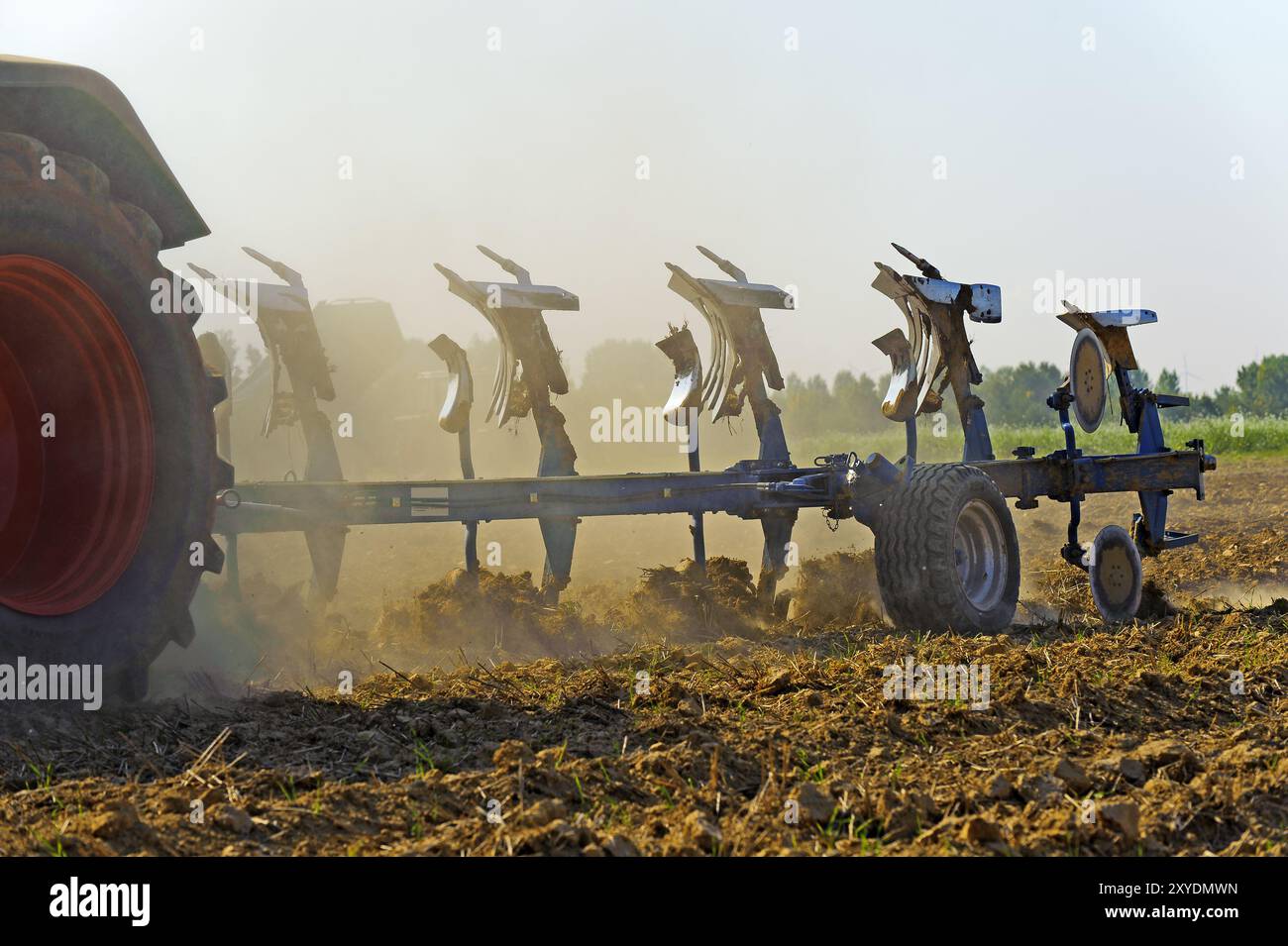 Tractor pulls a plough behind it Stock Photo - Alamy
