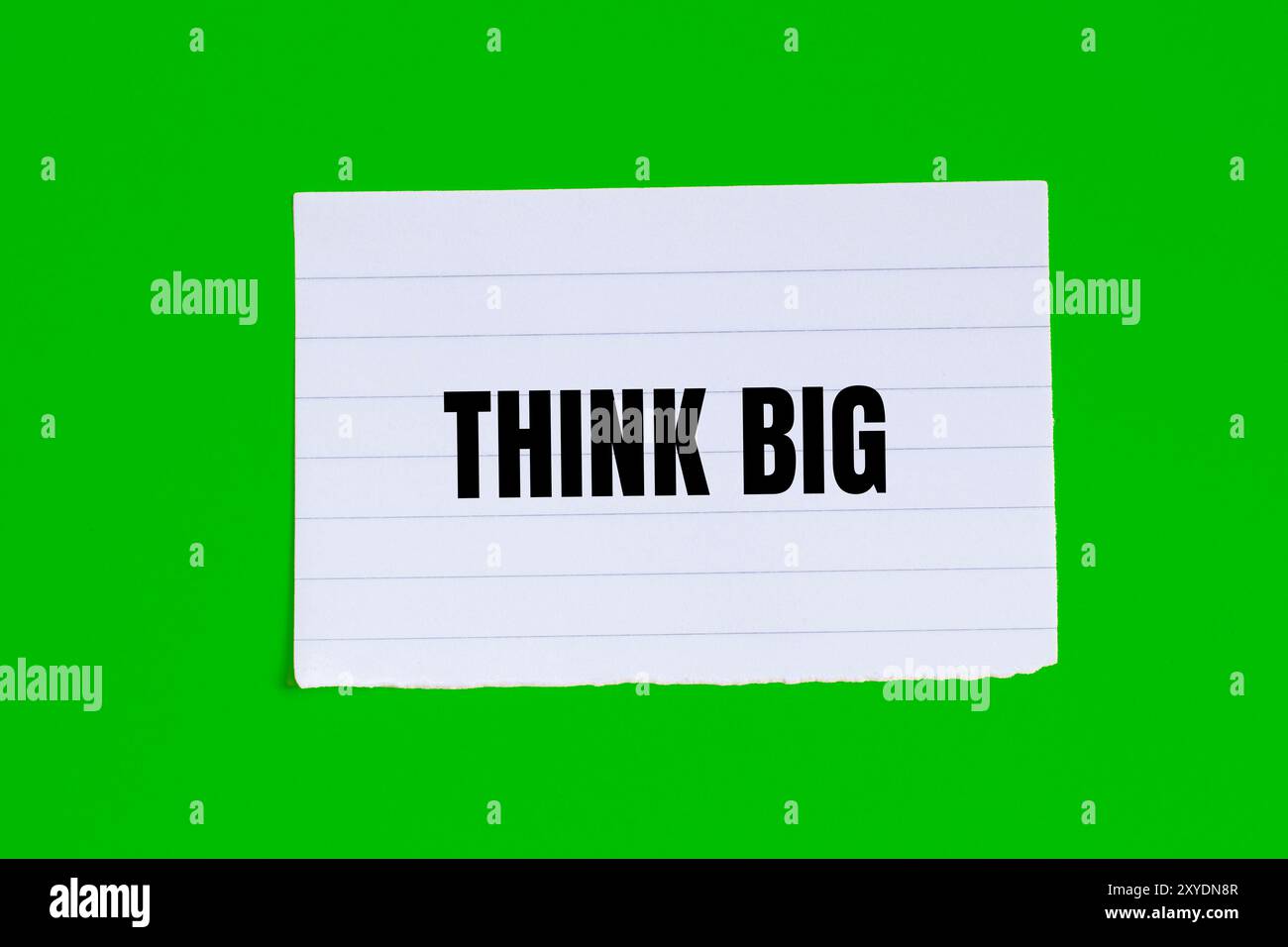 Think big message written on ripped torn paper piece with green ...