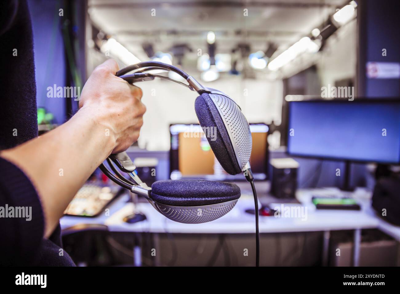 Young man holds headphones in the recording studio. Buttons, studio ...
