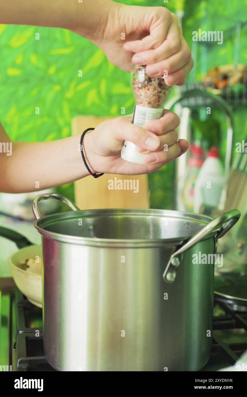 Women's hands salivate the contents of a metal pellet standing on a gas ...