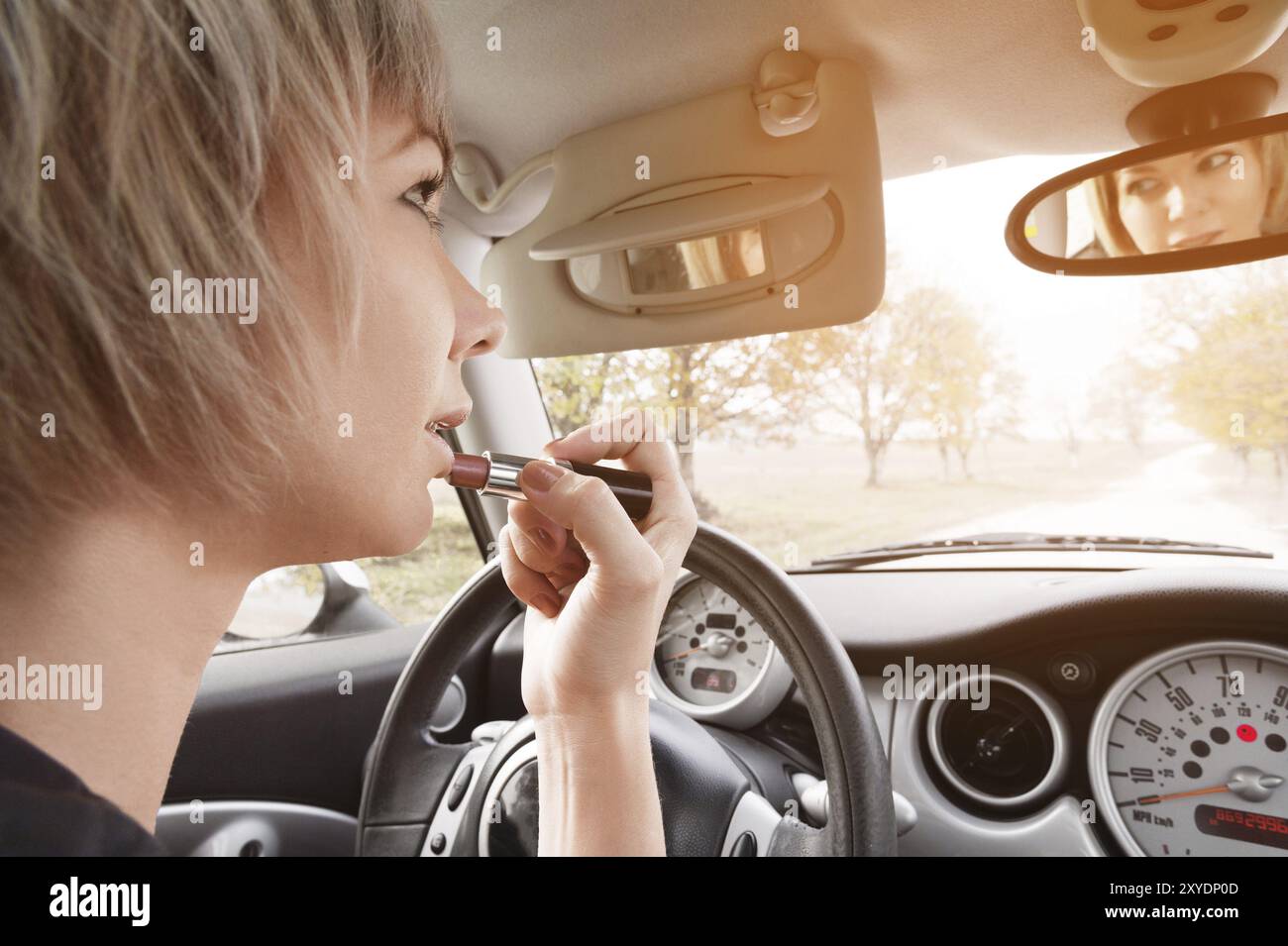 Cute blond woman with short hair coloring lips while sitting at the ...