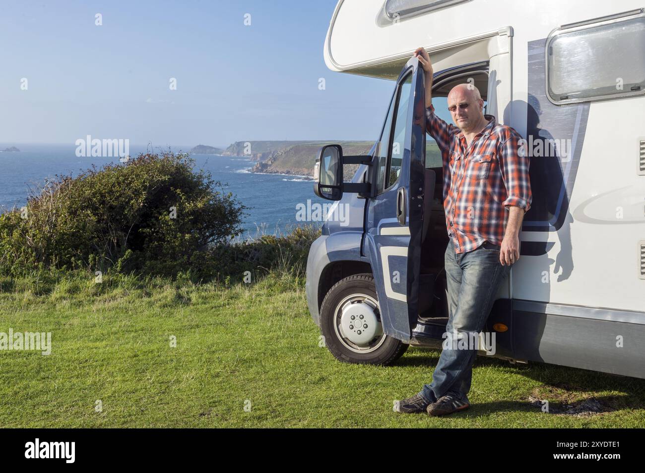 A middle-aged man stands at the open driver's door of his motorhome ...