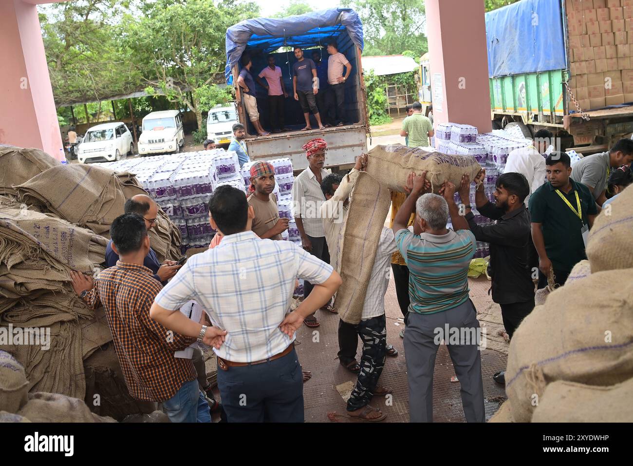 Laborers are carrying packets of food and stacking them in a truck as ...