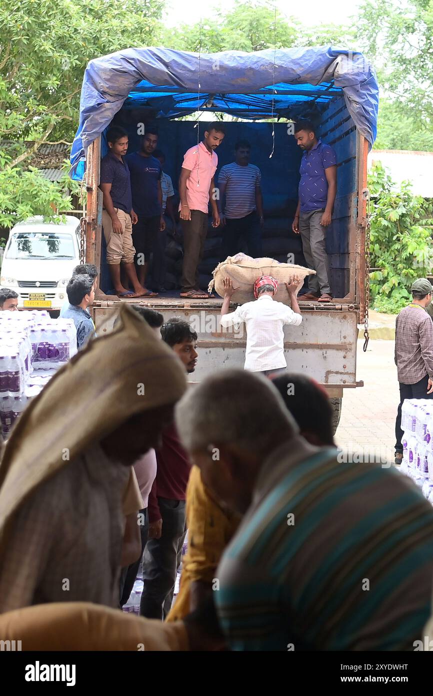 Laborers are carrying packets of food and stacking them in a truck as ...