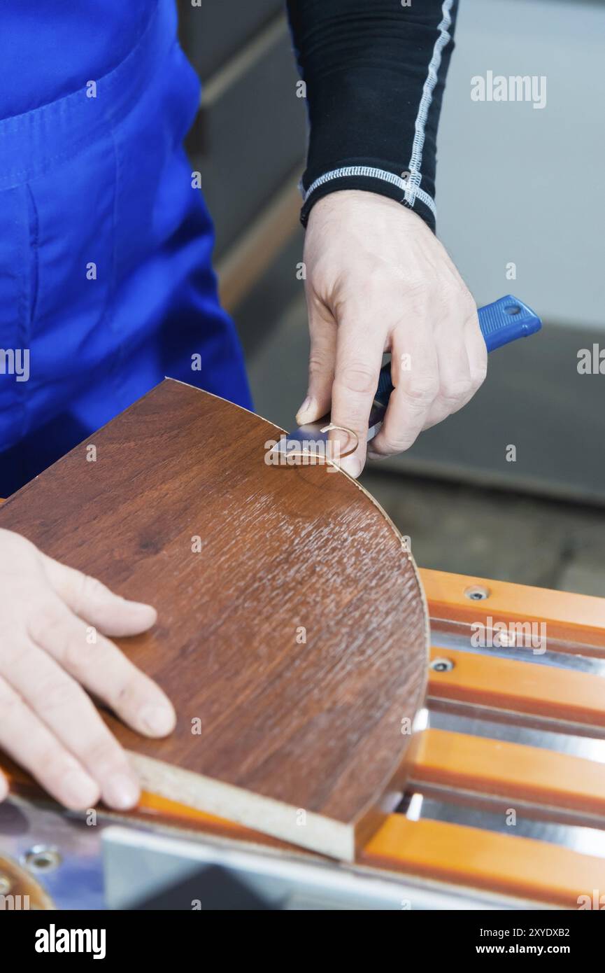 A professional carpenter processes the plastic edges of the countertop ...