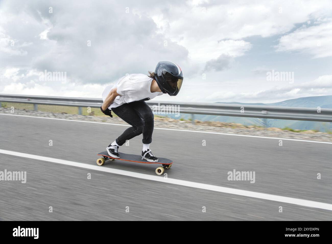 A young guy in a full-face helmet rides a country road at high speed in ...