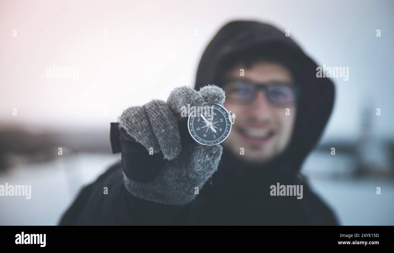 Young smiling man holds up a compass. Wintertime, gloves and hood Stock ...