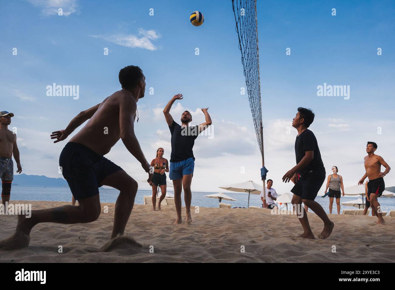 Multinational teams of people play beach volleyball on beach in summer ...
