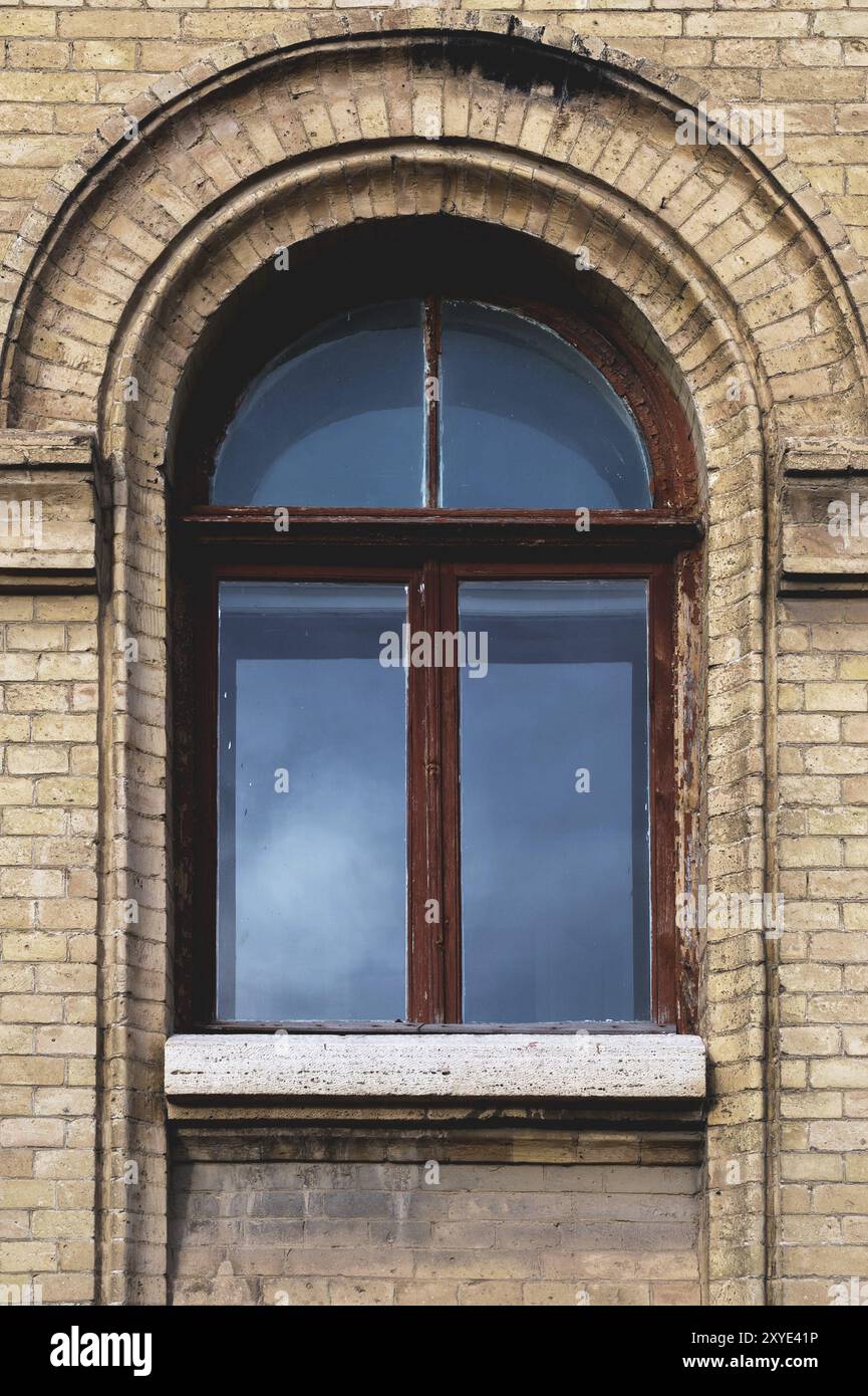 Vintage arched window in the wall of yellow brick. Black glass in a ...