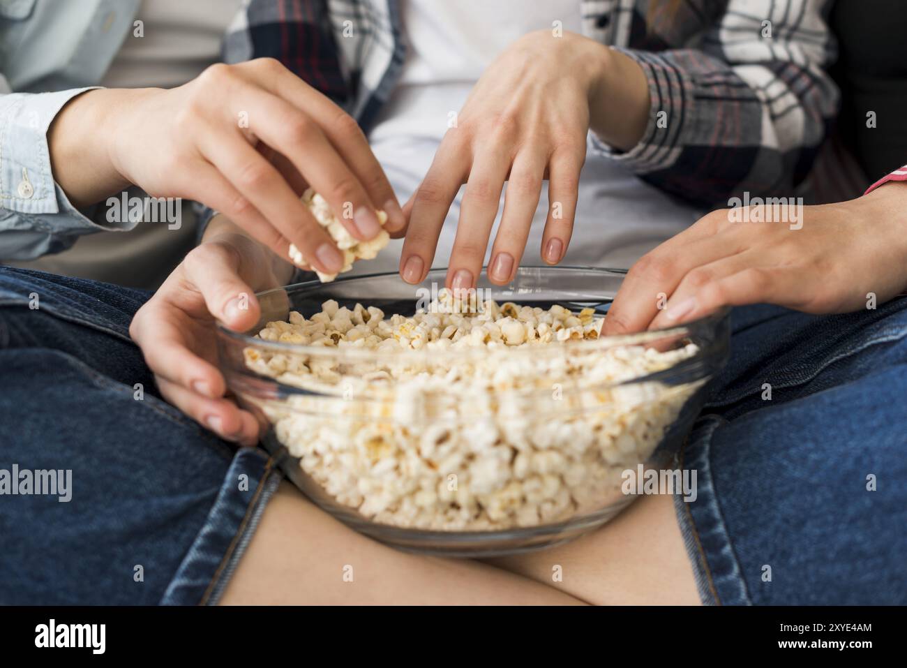 Bowl with popcorn hands girl sitting cross legged sofa Stock Photo - Alamy