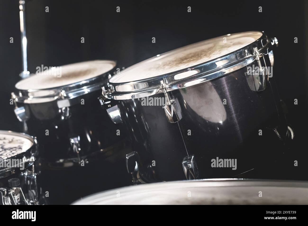 Closeup view of a drum set in a dark studio. Black drum barrels with ...