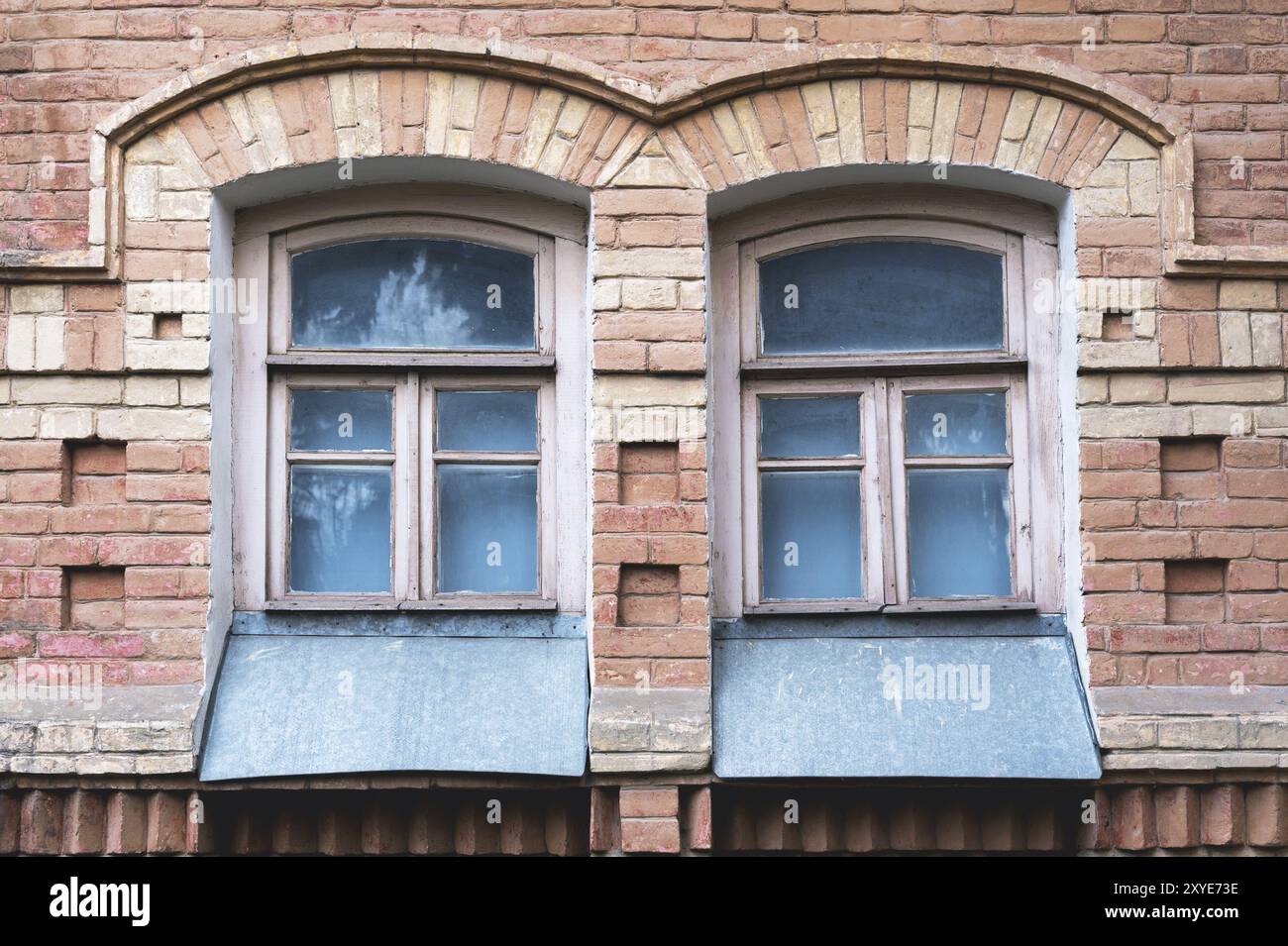 Two vintage arched windows in a wall of yellow bricks. Green, the ...