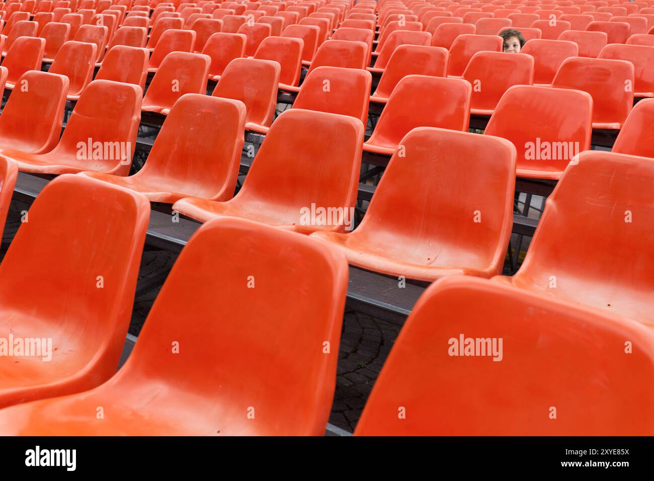 Child hiding behind red chairs Stock Photo - Alamy