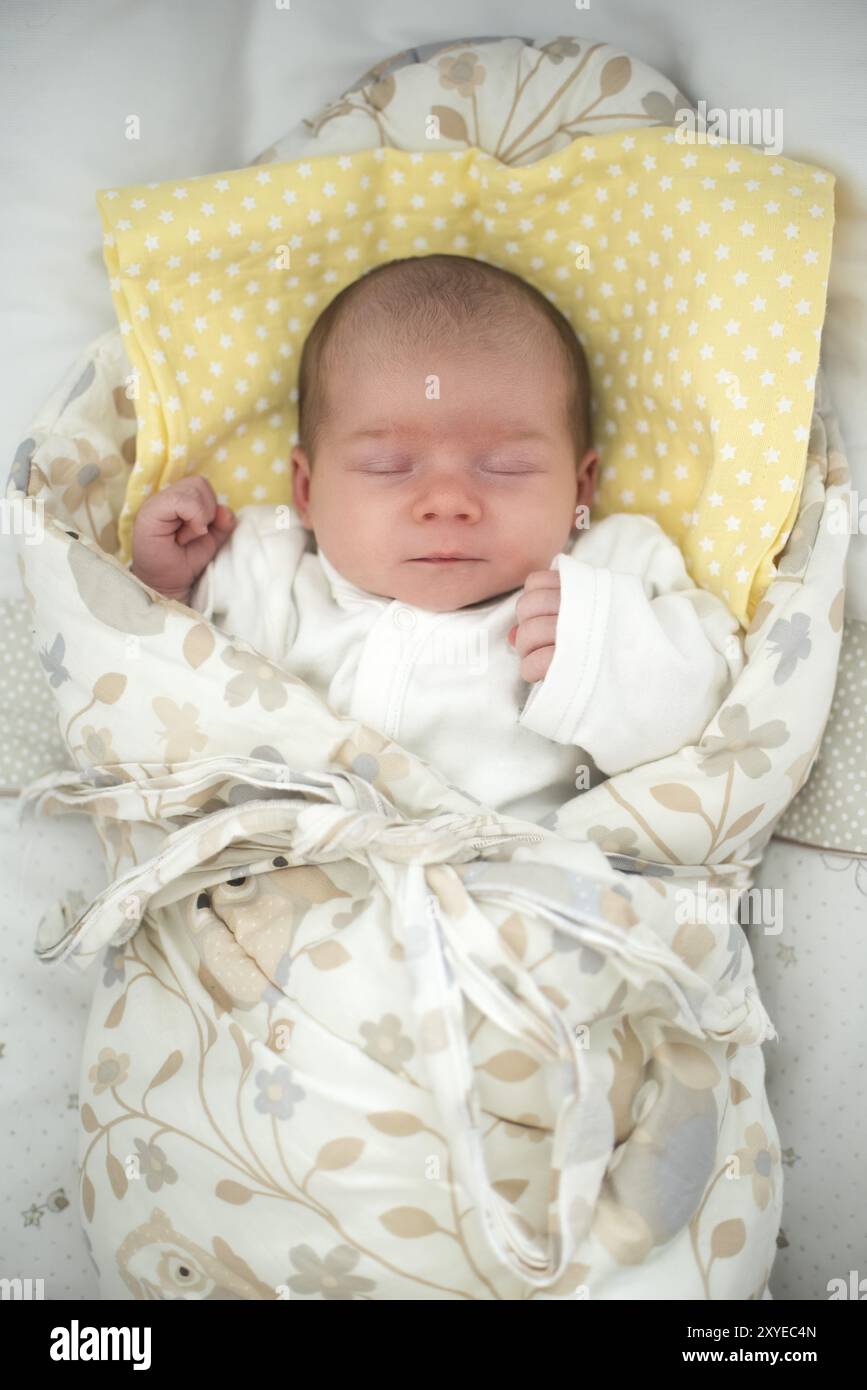 Cute newborn baby sleeping in swaddle wrap with smile on her face ...