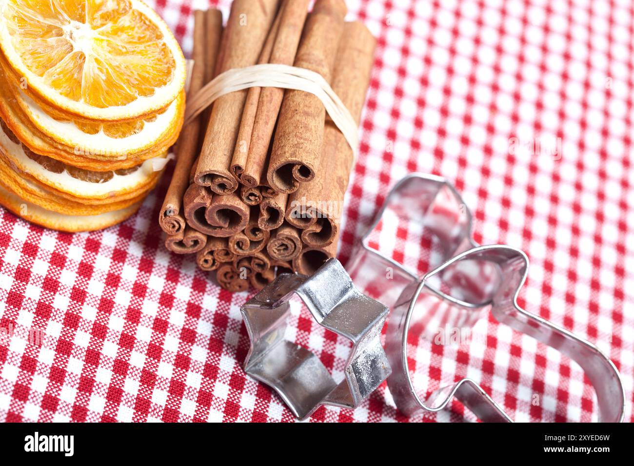 Orange, cinnamon, aniseed and biscuit cutter on checked cloth Stock ...