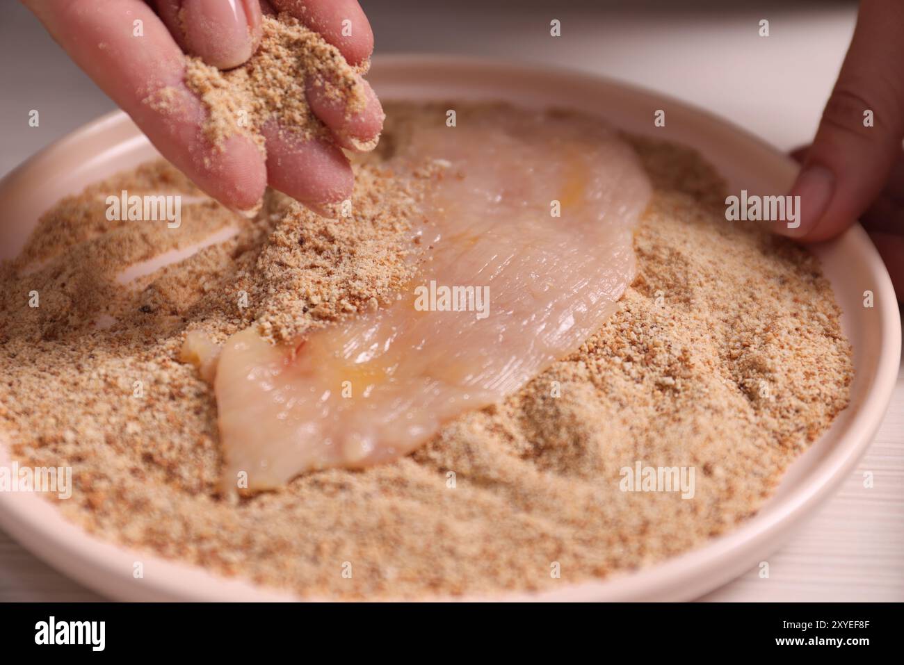 Making schnitzel. Woman coating slice of meat with bread crumbs at ...