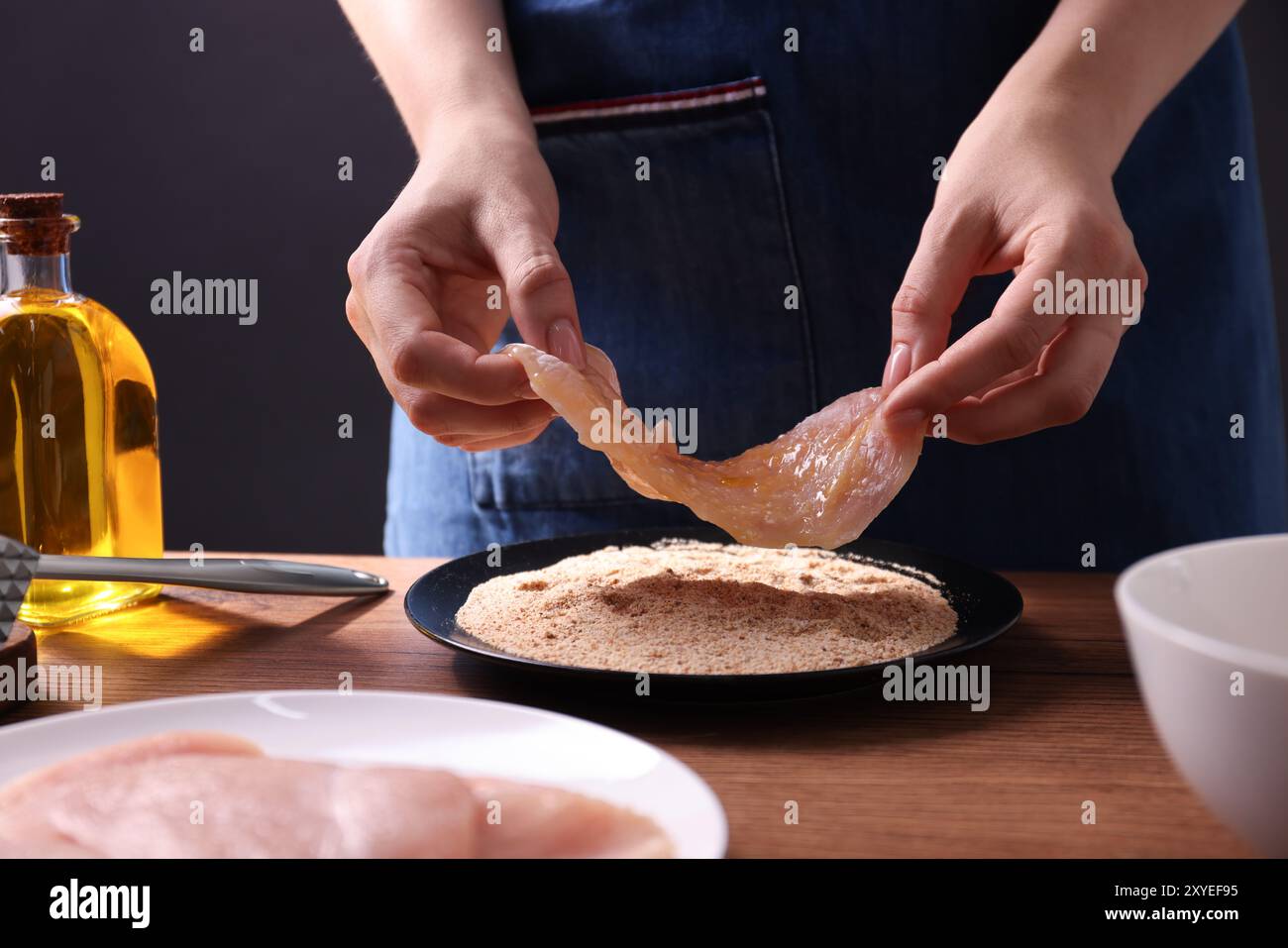 Making schnitzel. Woman coating slice of meat with bread crumbs at ...